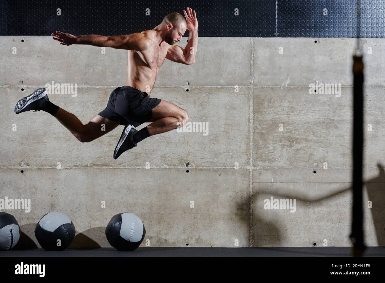 A muscular man captured in air as he jumps in a modern gym, showcasing ...