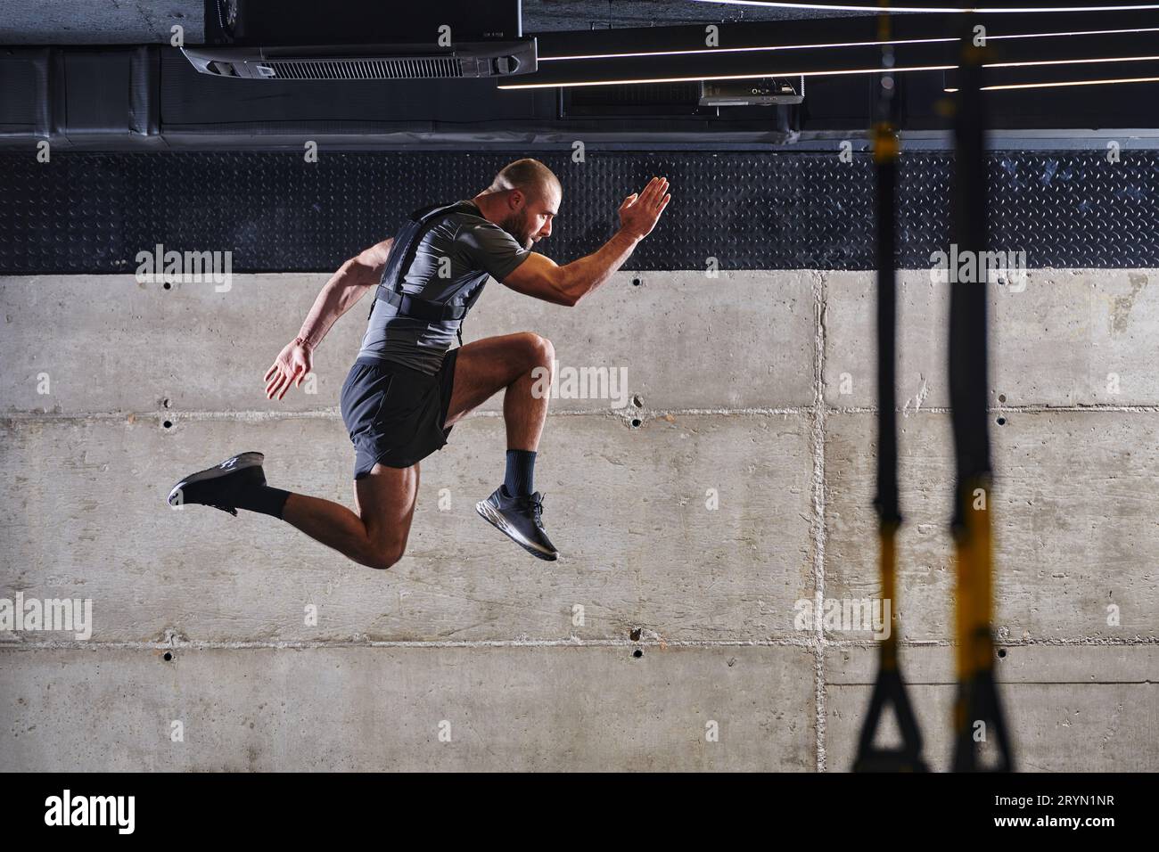 A muscular man captured in air as he jumps in a modern gym, showcasing ...