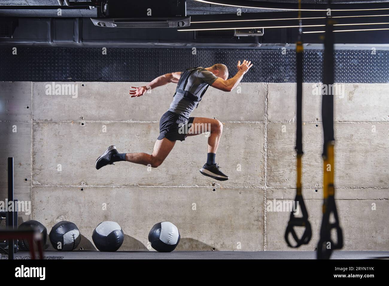 A muscular man captured in air as he jumps in a modern gym, showcasing ...