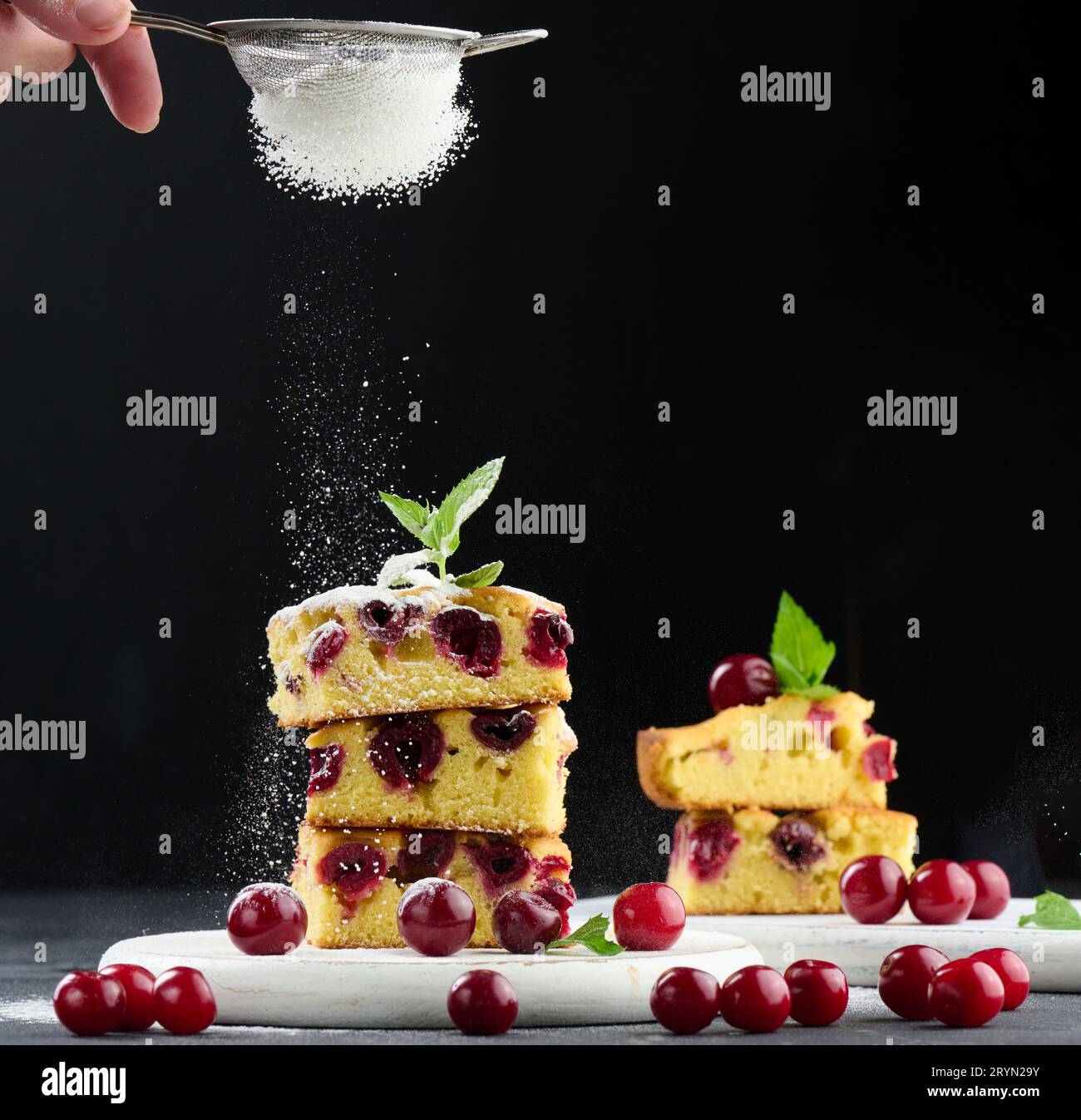 Baked sponge cake with cherries sprinkled with powdered sugar, black ...