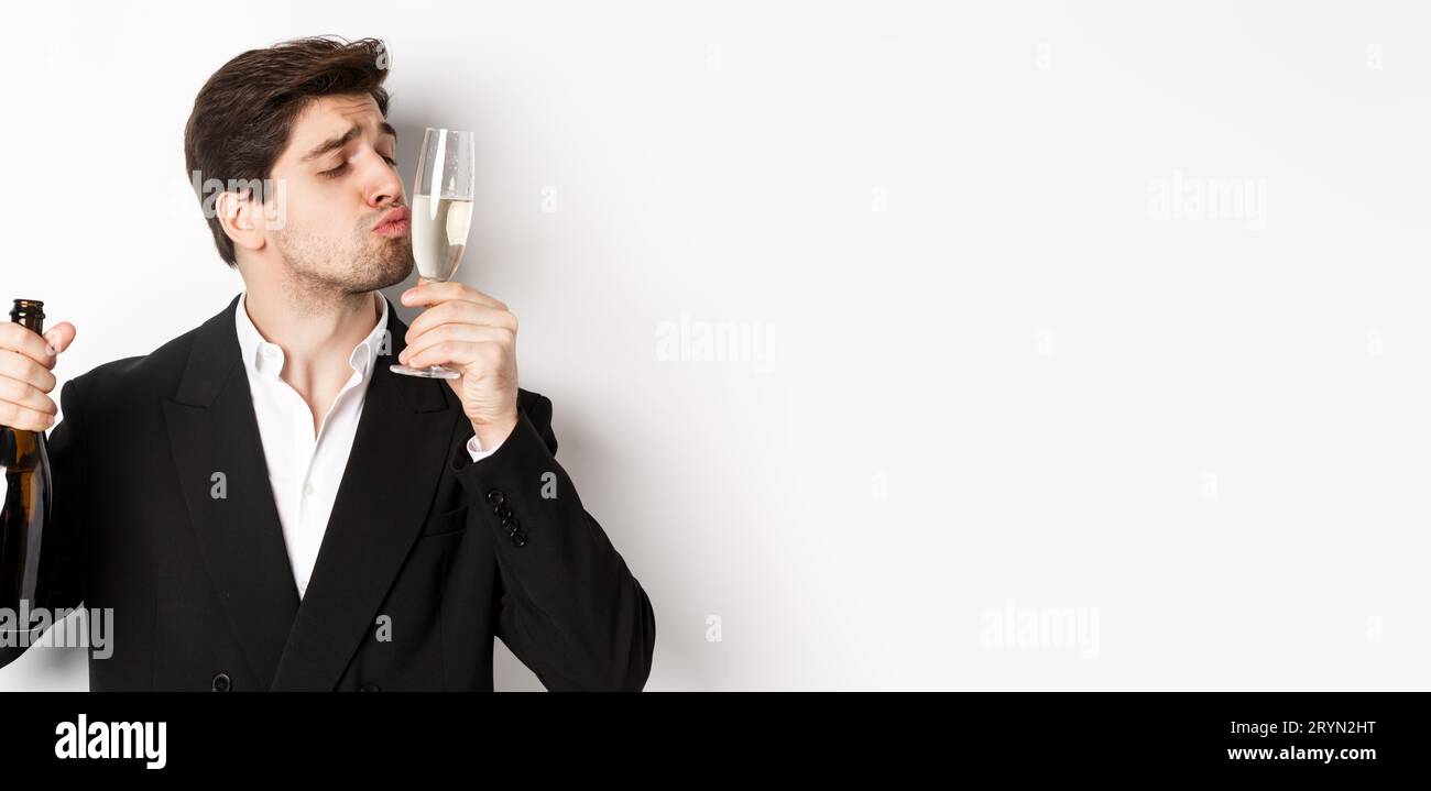 Close-up of handsome man in suit, kissing glass with champagne, getting ...