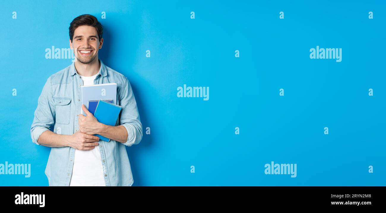 Young man holding notebooks and study material, smiling happy, standing ...