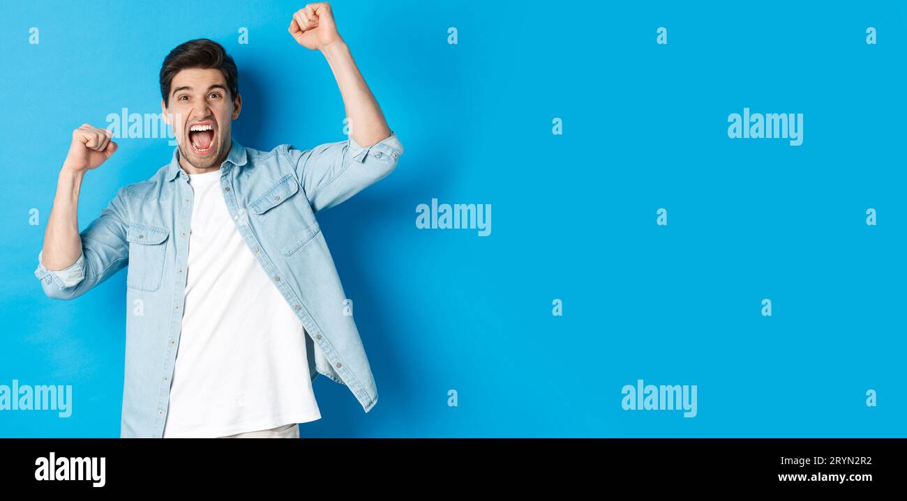 Cheerful guy making fist pumps and rooting for someone, shouting for ...