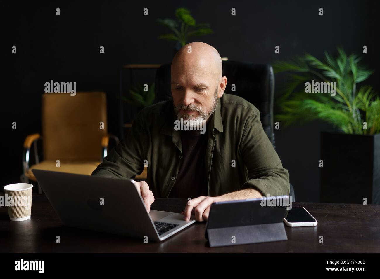 Man diligently working on his laptop from the comfort of his home. With ...