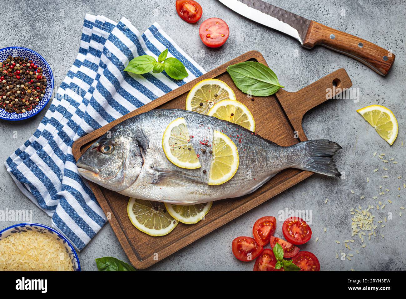 Raw fish dorado with ingredients lemon, fresh basil, cut cherry ...