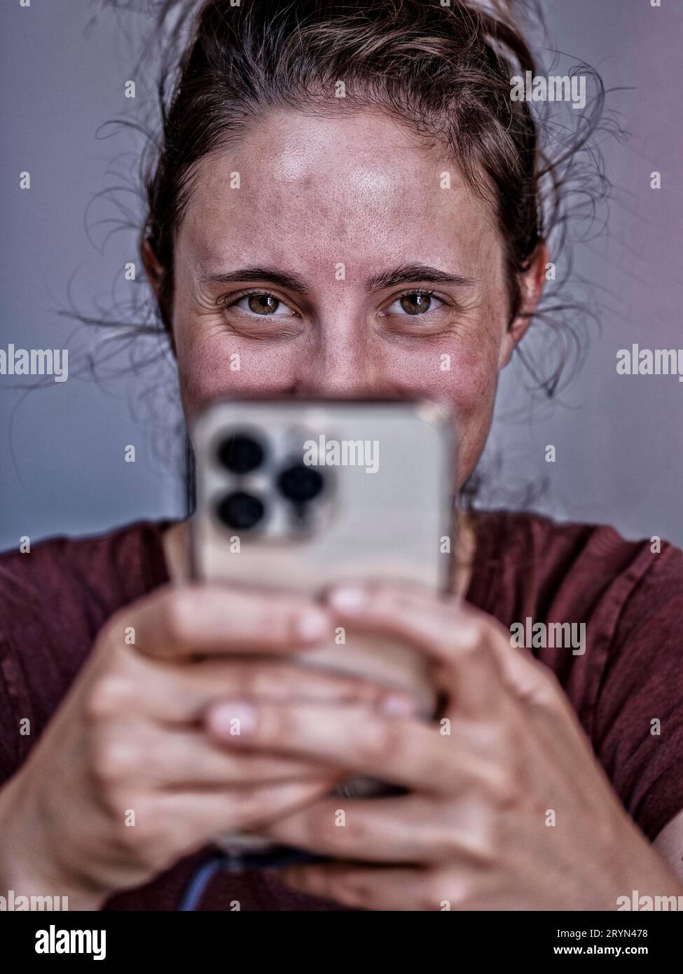 Woman with mischievous smile looks over her mobile phone Stock Photo ...