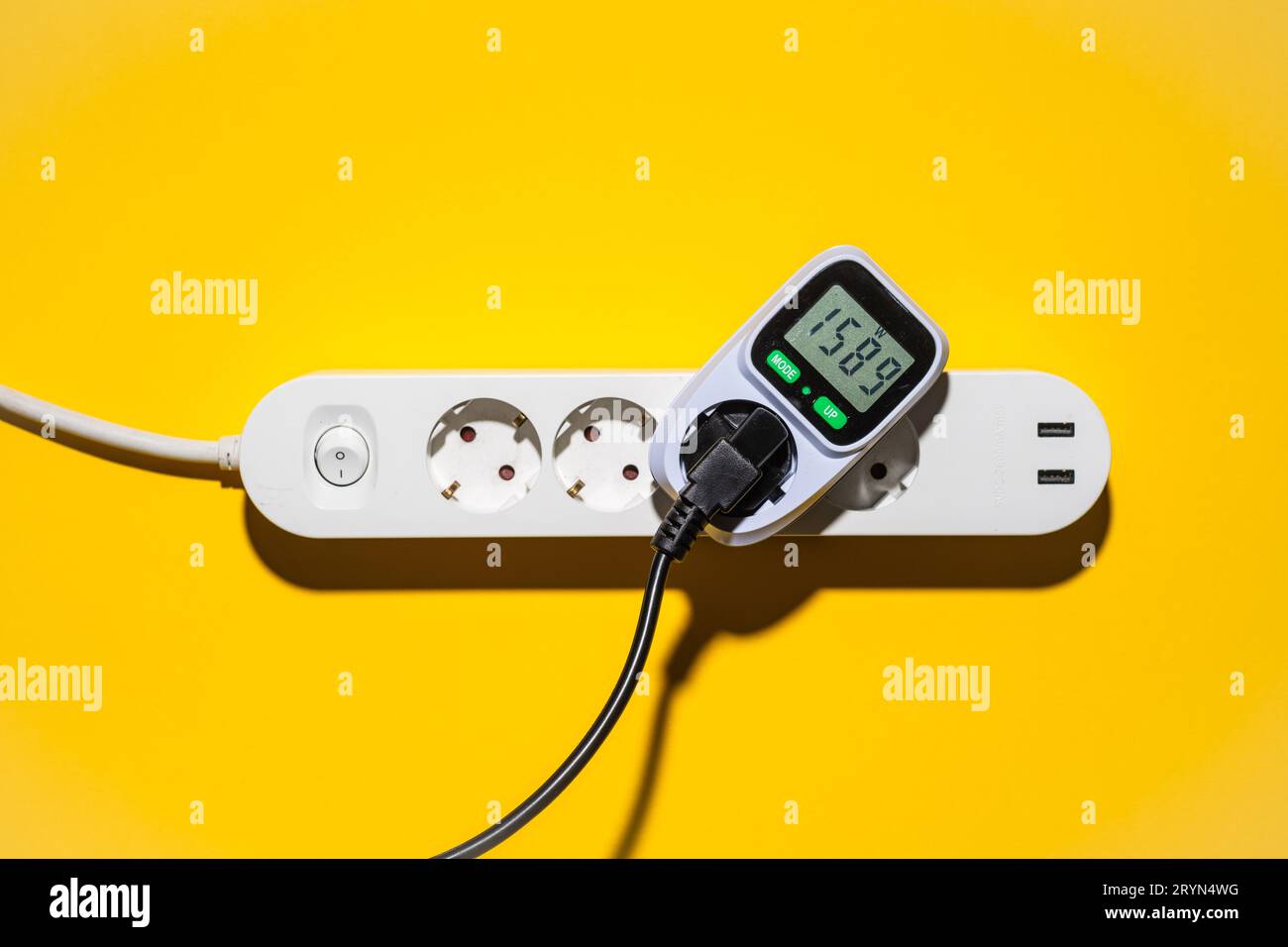 Top view of an energy cost meter in a power strip against a yellow ...