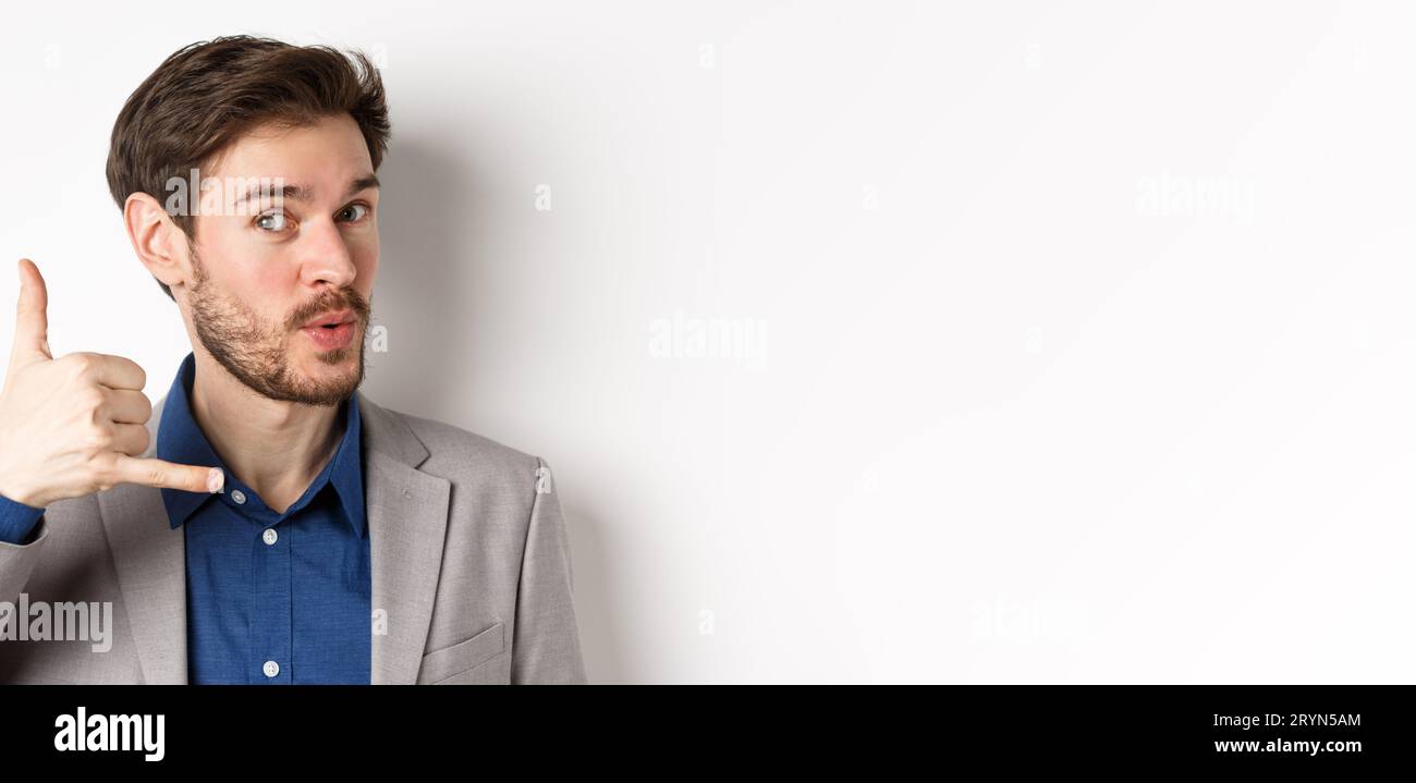 Handsome macho guy in suit showing phone sign near ear, flirting and ...