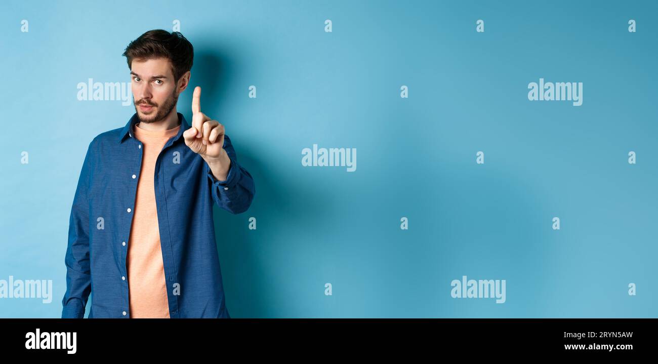 Image of young man give warning, teaching a lesson, raising one finger ...