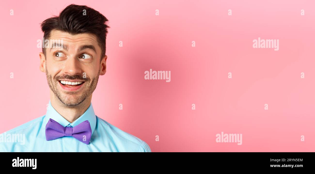 Close-up of amused smiling guy with moustache, pointing and looking ...