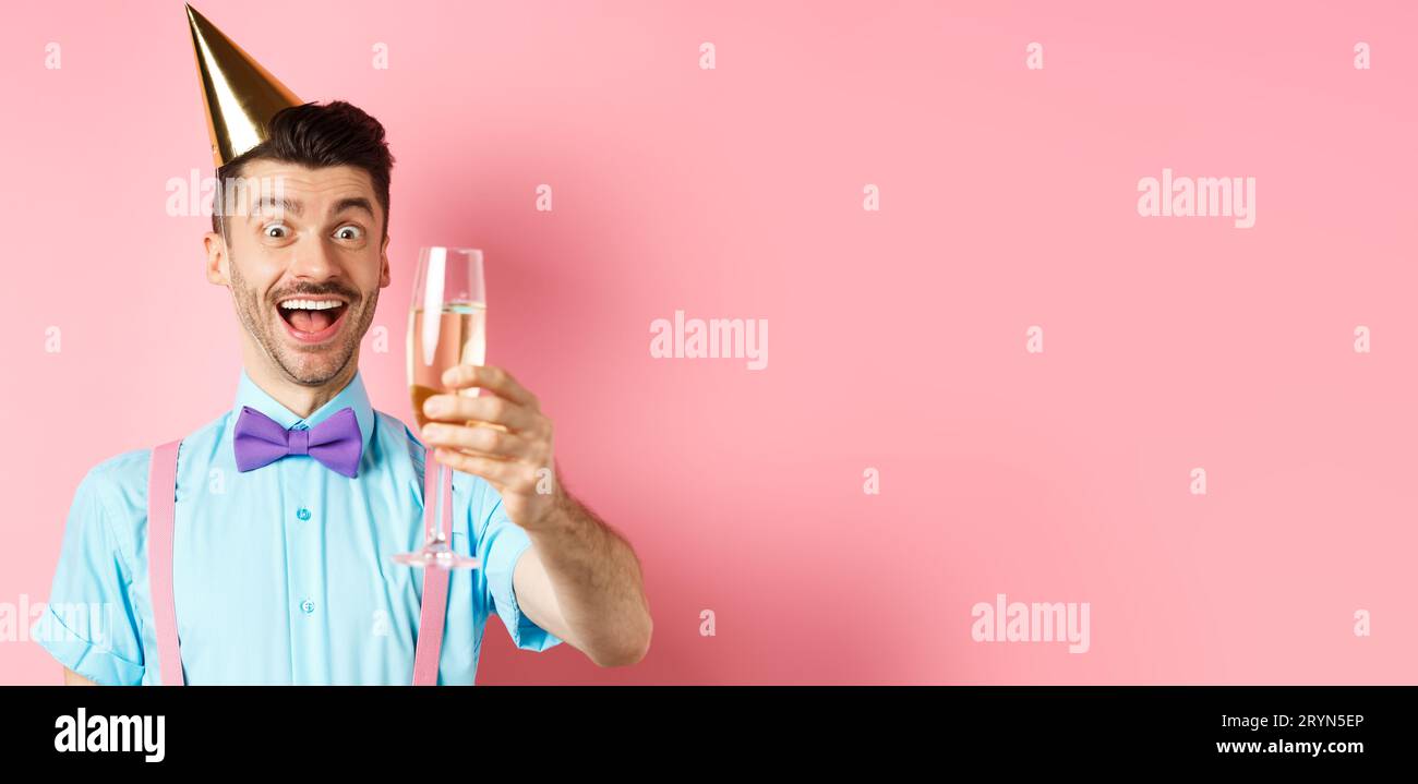 Holidays and celebration concept. Excited birthday guy raising glass of ...