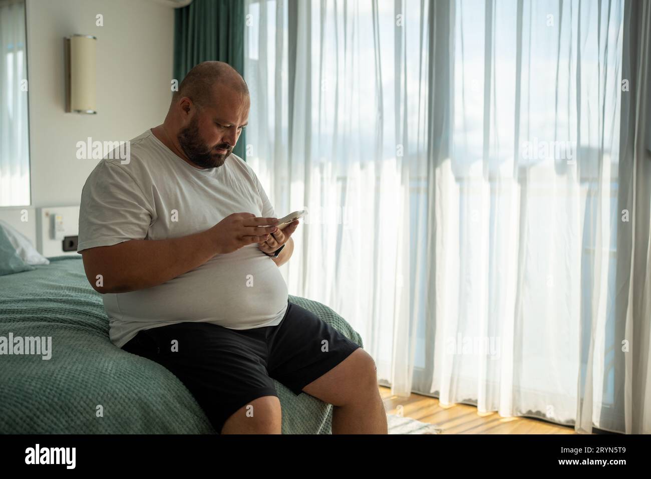 Fat bearded bald guy with smartphone chatting, dials number, types ...