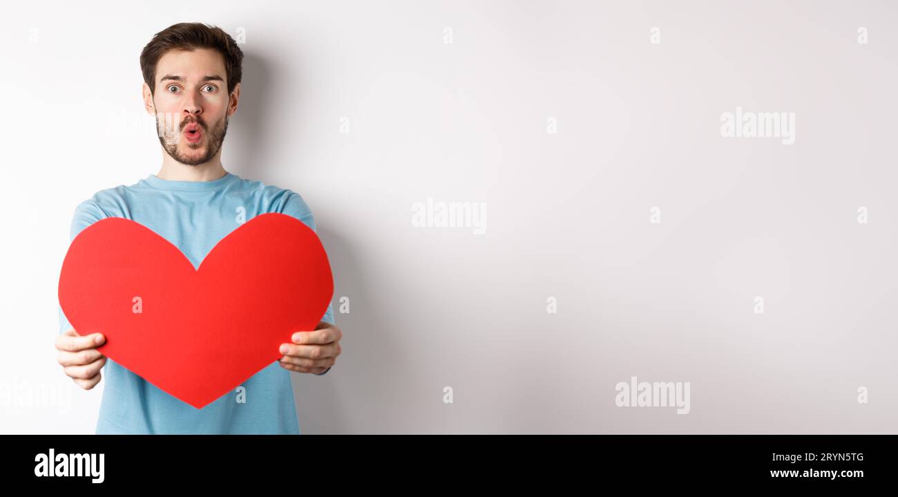 Young handsome man showing big red valentines day heart, being in love ...