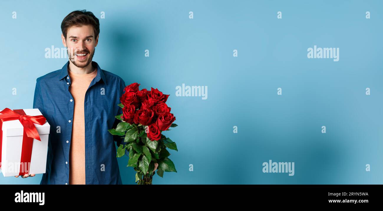 Love and relationship concept. Happy young man bring flowers and gift ...