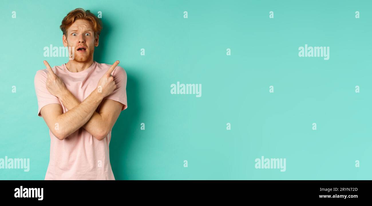 Nervous guy with red hair staring indecisive, cross arms and pointing ...