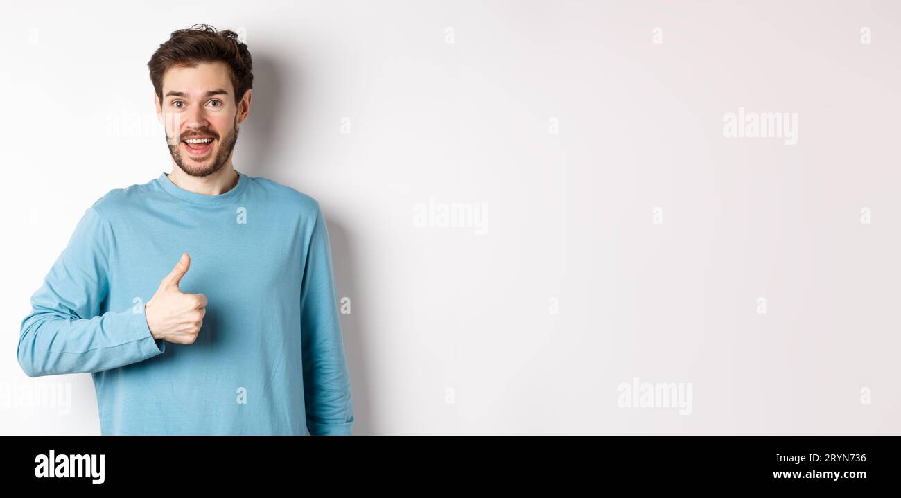 Cheerful young man agree and say yes, show thumb up in approval ...