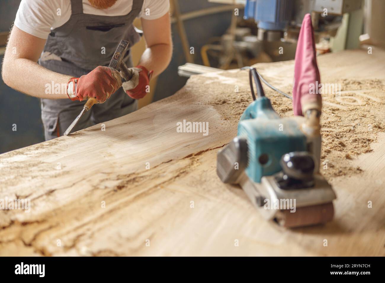 Close up of carpenter working with chisel while cutting wooden plank in ...