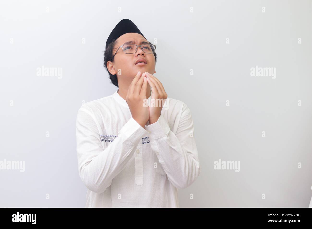 Portrait of young millennial Asian muslim man praying earnestly with ...