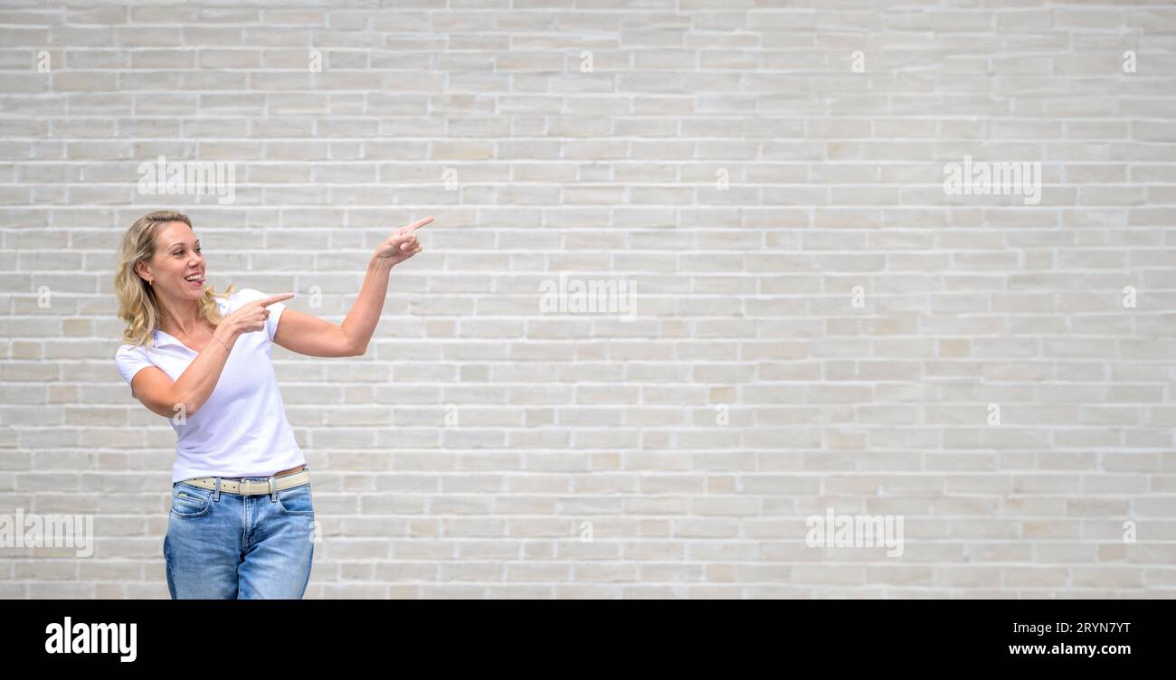 Promotional photo of an attractive friendly woman pointing to the right ...