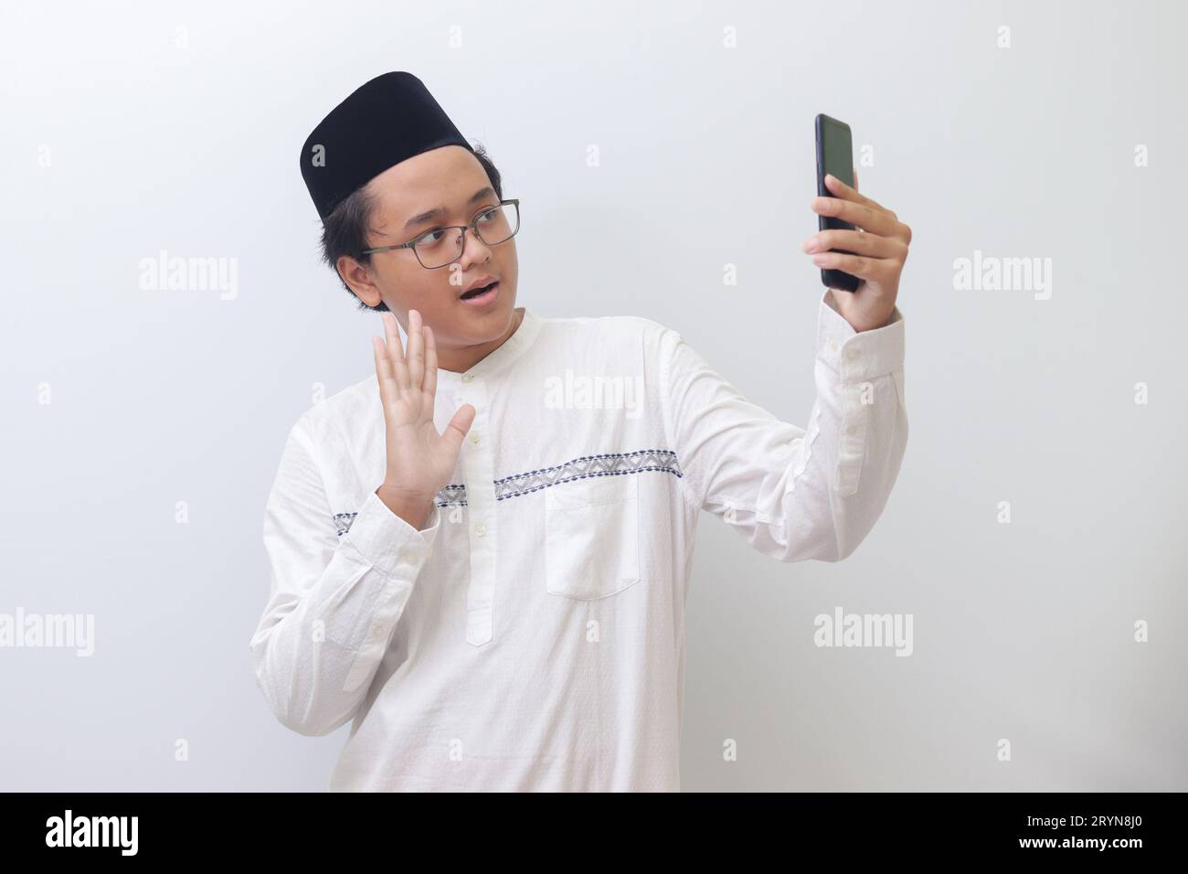 Portrait of smiling young Asian muslim man taking picture of himself or ...