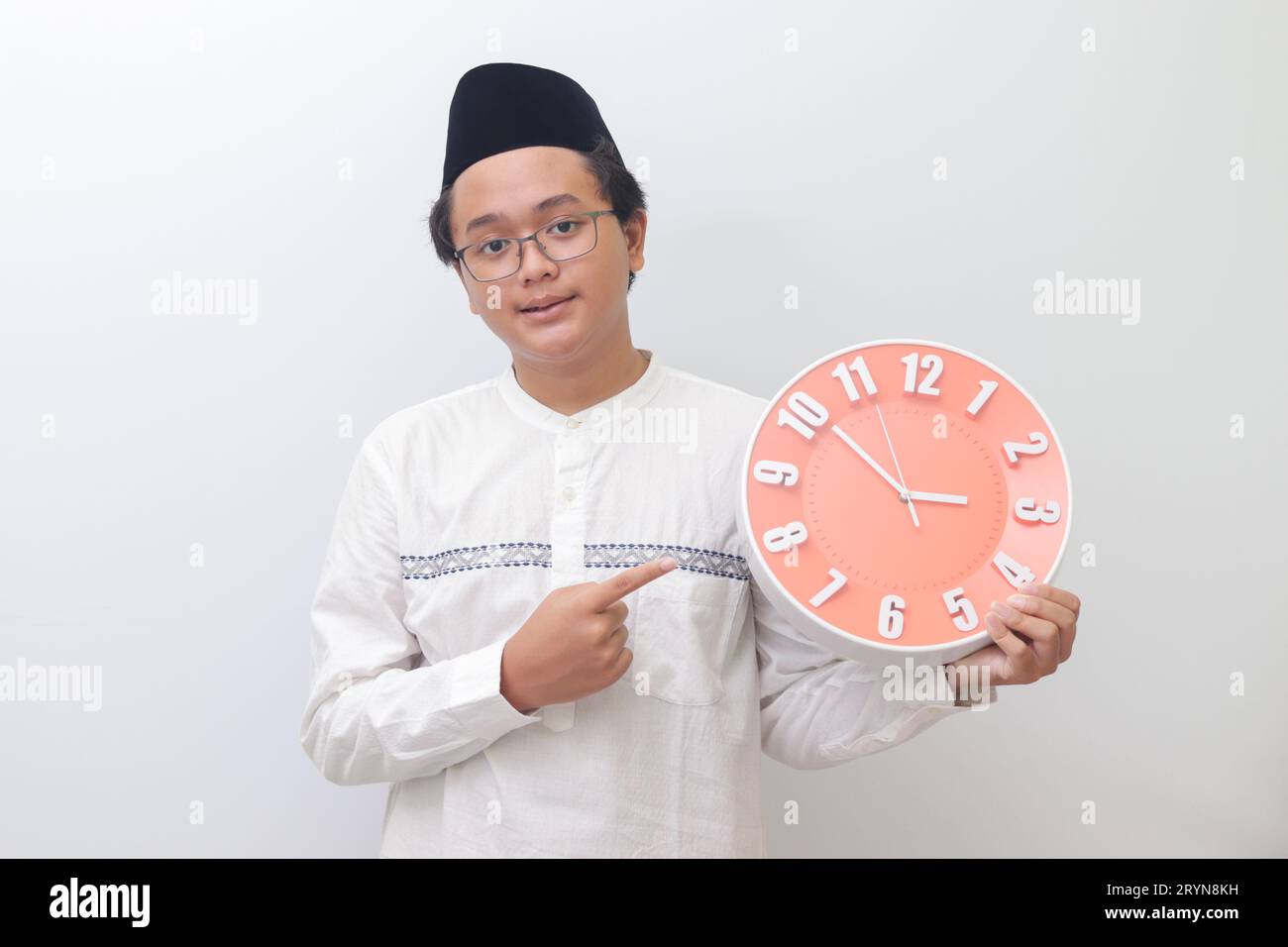 Portrait of young attractive Asian muslim man pointing and holding a ...