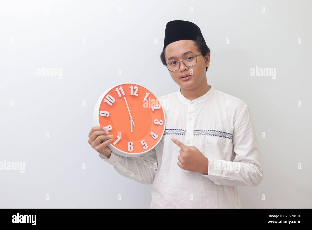 Portrait of young attractive Asian muslim man pointing and holding a ...