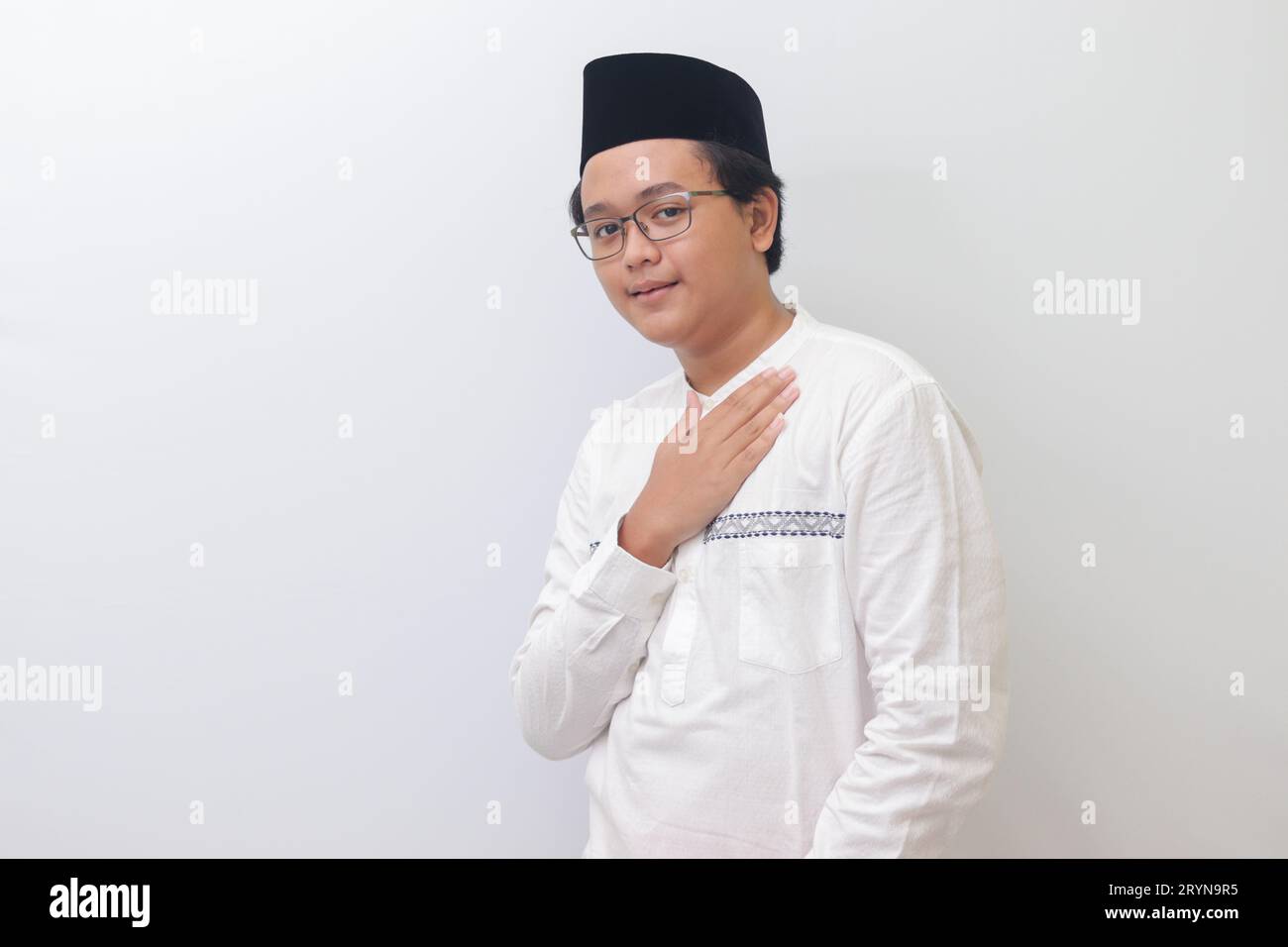 Portrait of young Asian muslim man placing hand on heart, feeling very ...