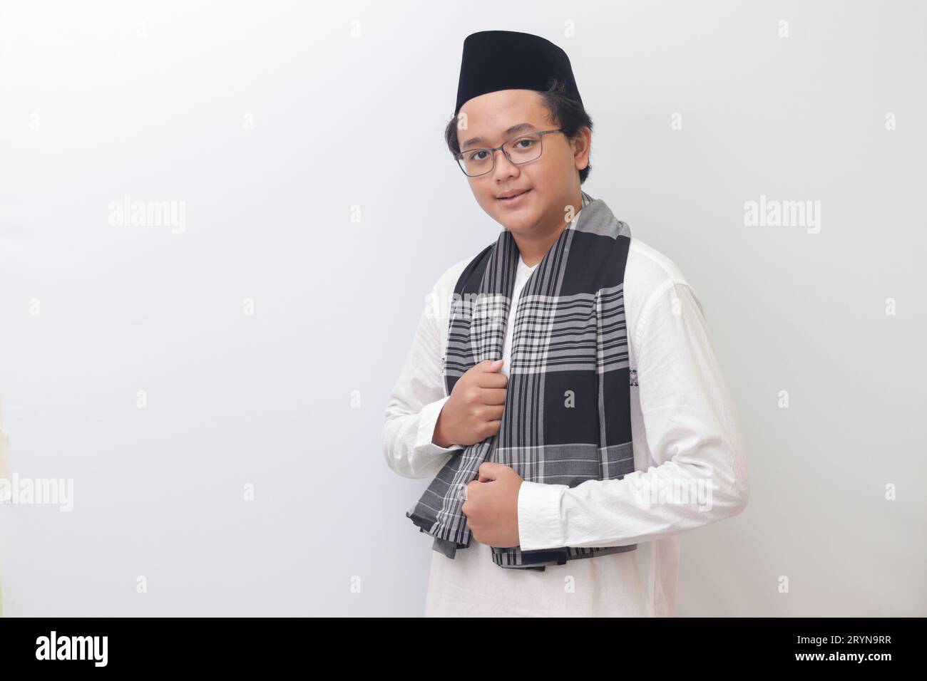 Portrait of young Asian muslim man standing with cool pose and holding ...