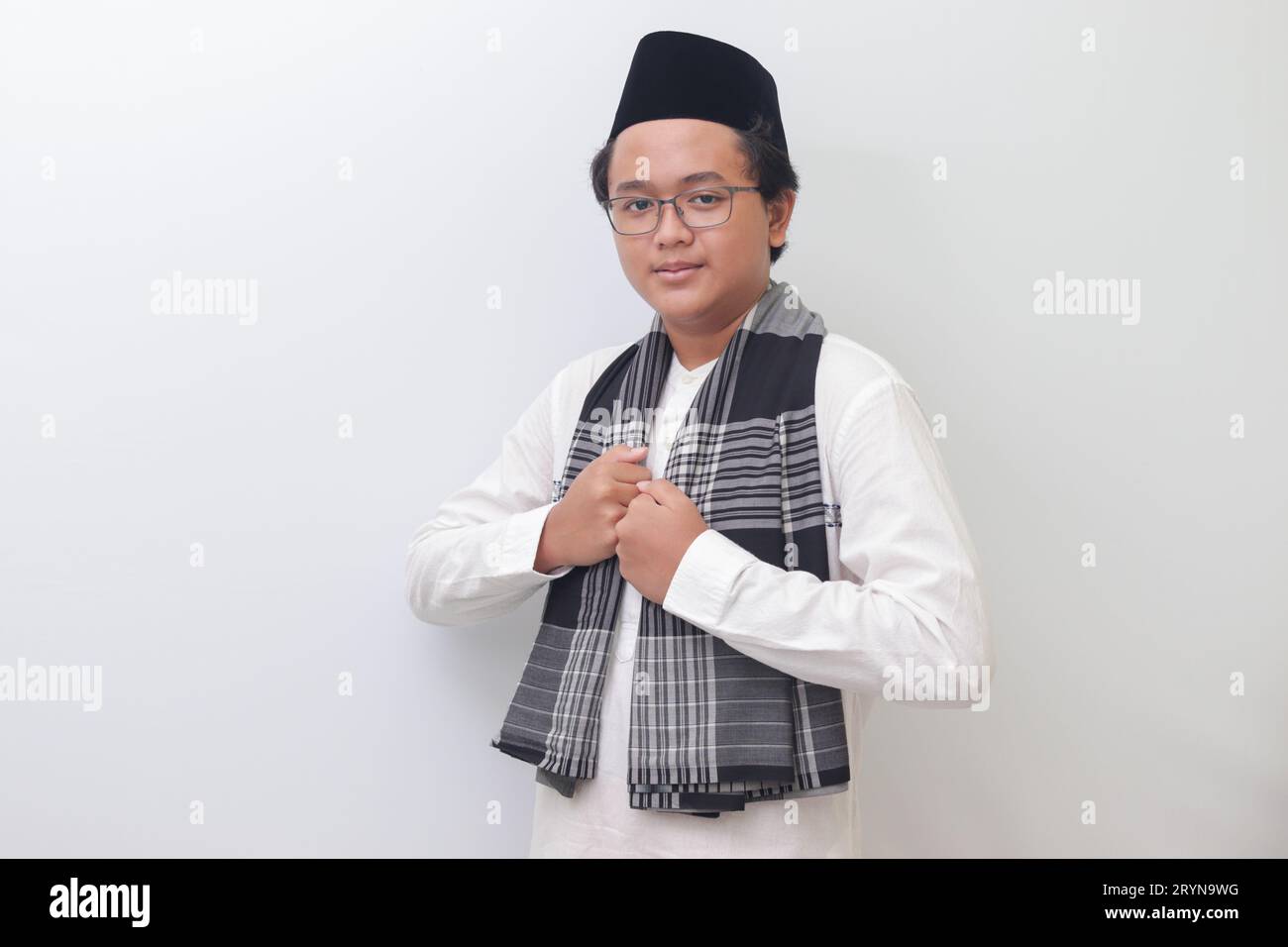 Portrait of young Asian muslim man standing with cool pose and holding ...