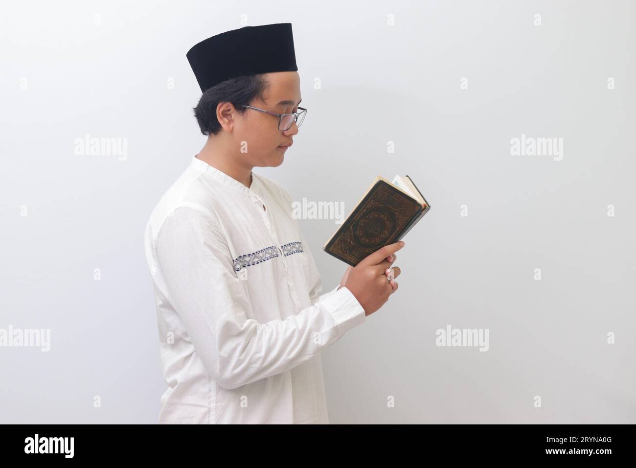 Portrait of young Asian muslim man reading and reciting Holy book of ...