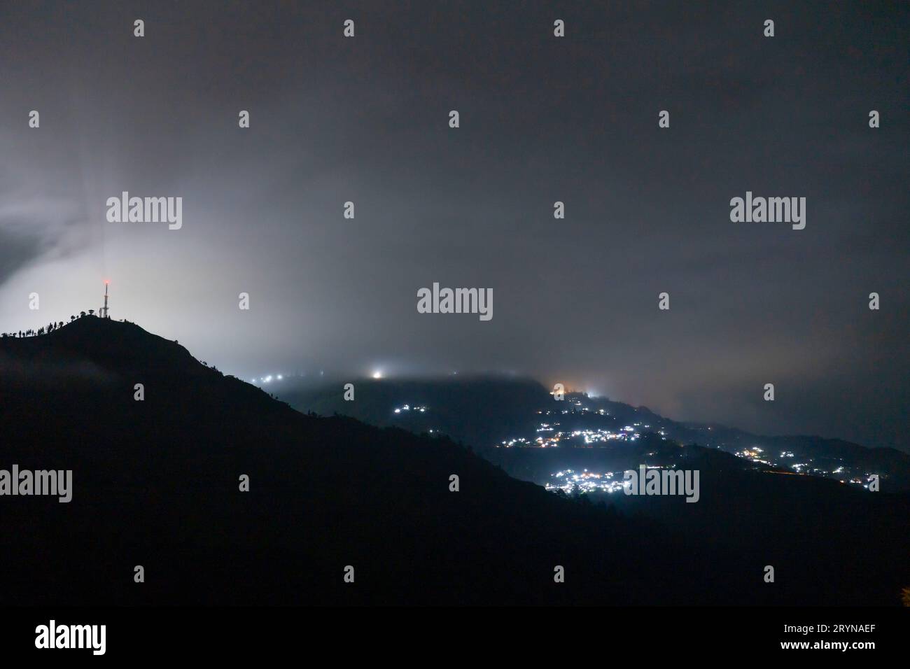 Night long exposure shot showing fog rolling over hills with village in ...