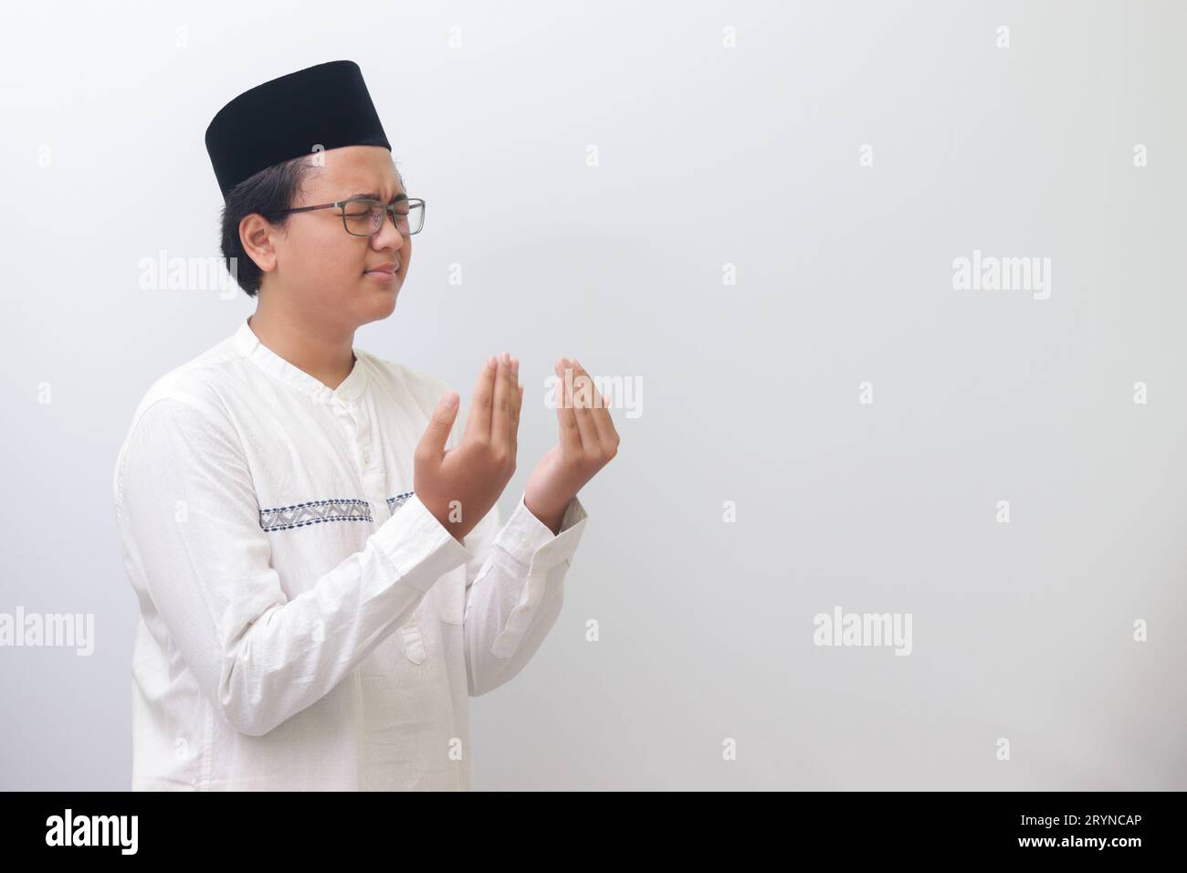 Portrait of young millennial Asian muslim man praying earnestly with ...