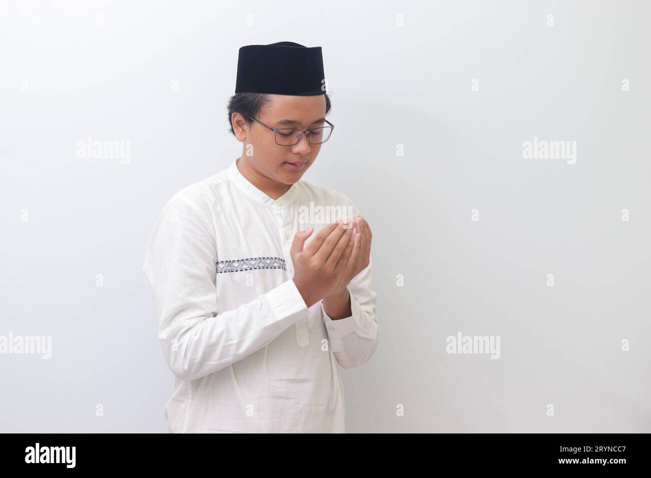 Portrait of young millennial Asian muslim man praying earnestly with ...