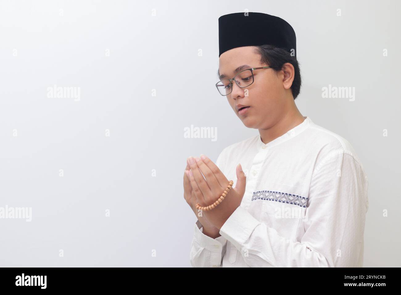 Portrait of young millennial Asian muslim man praying earnestly with ...