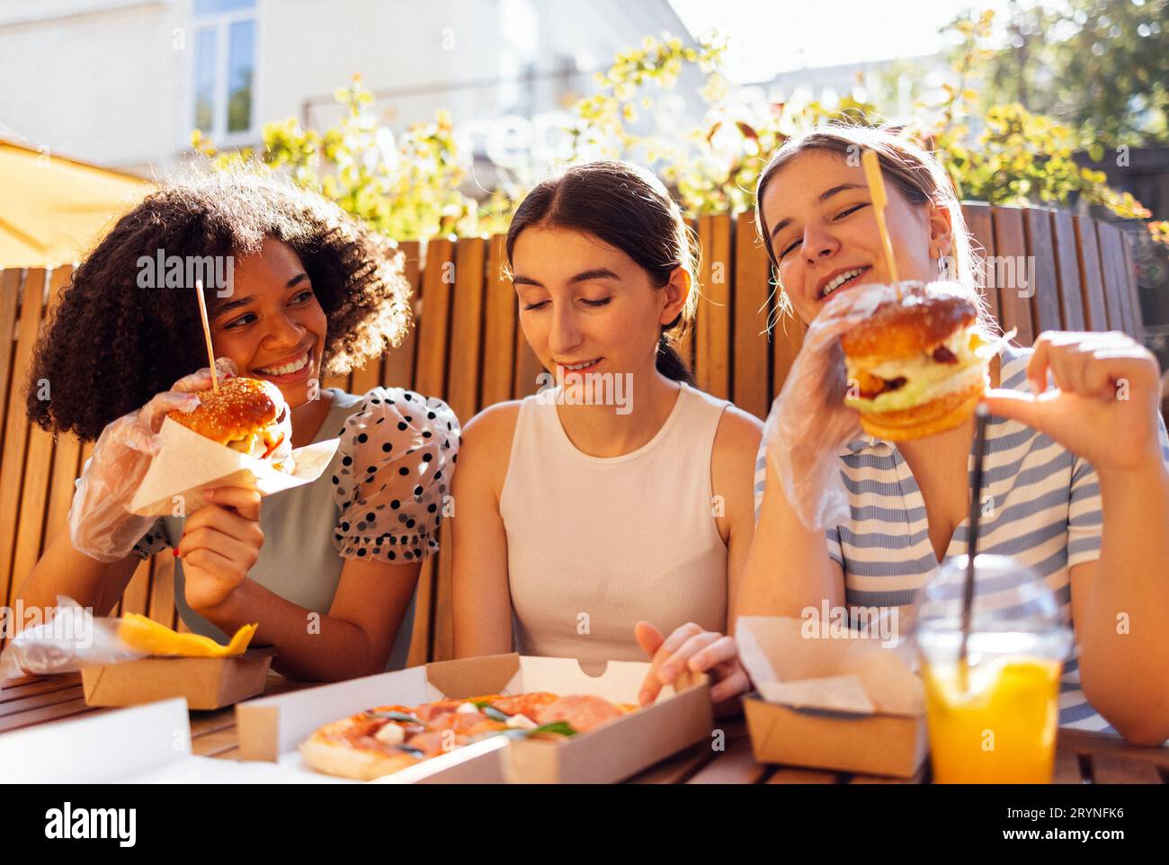 Heerful happy female friends of different nationalities snacking on ...