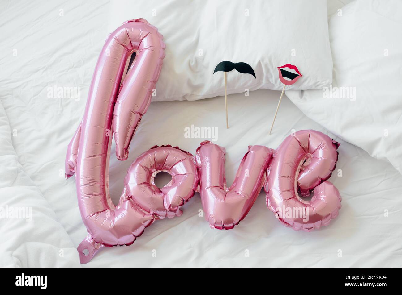 Inflatable big letters LOVE and props with mustache and lips on the bed ...