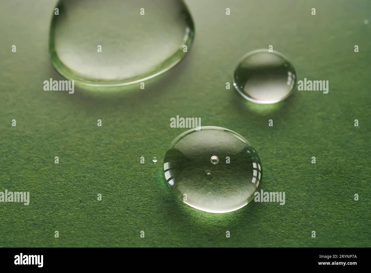 Three drops of liquid on a green background Stock Photo - Alamy