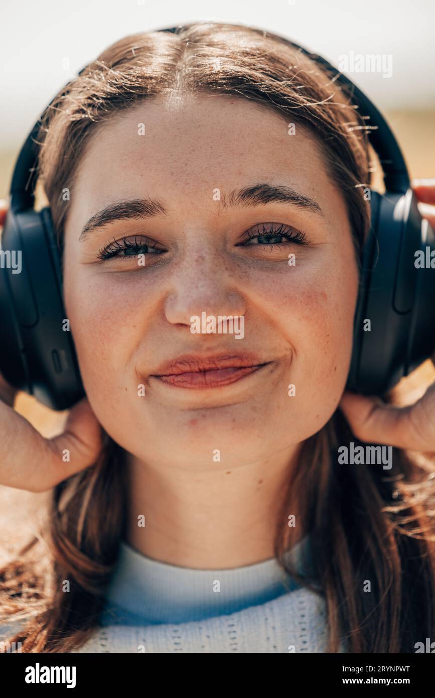 Face of pretty young woman listening to music with wireless headphones ...
