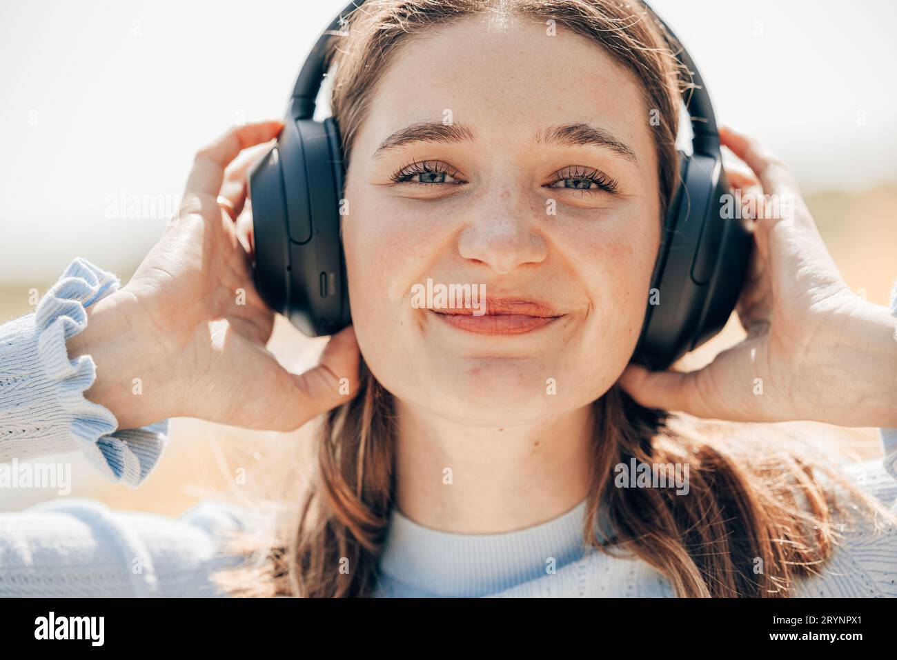 Face of pretty young woman listening to music with wireless headphones ...