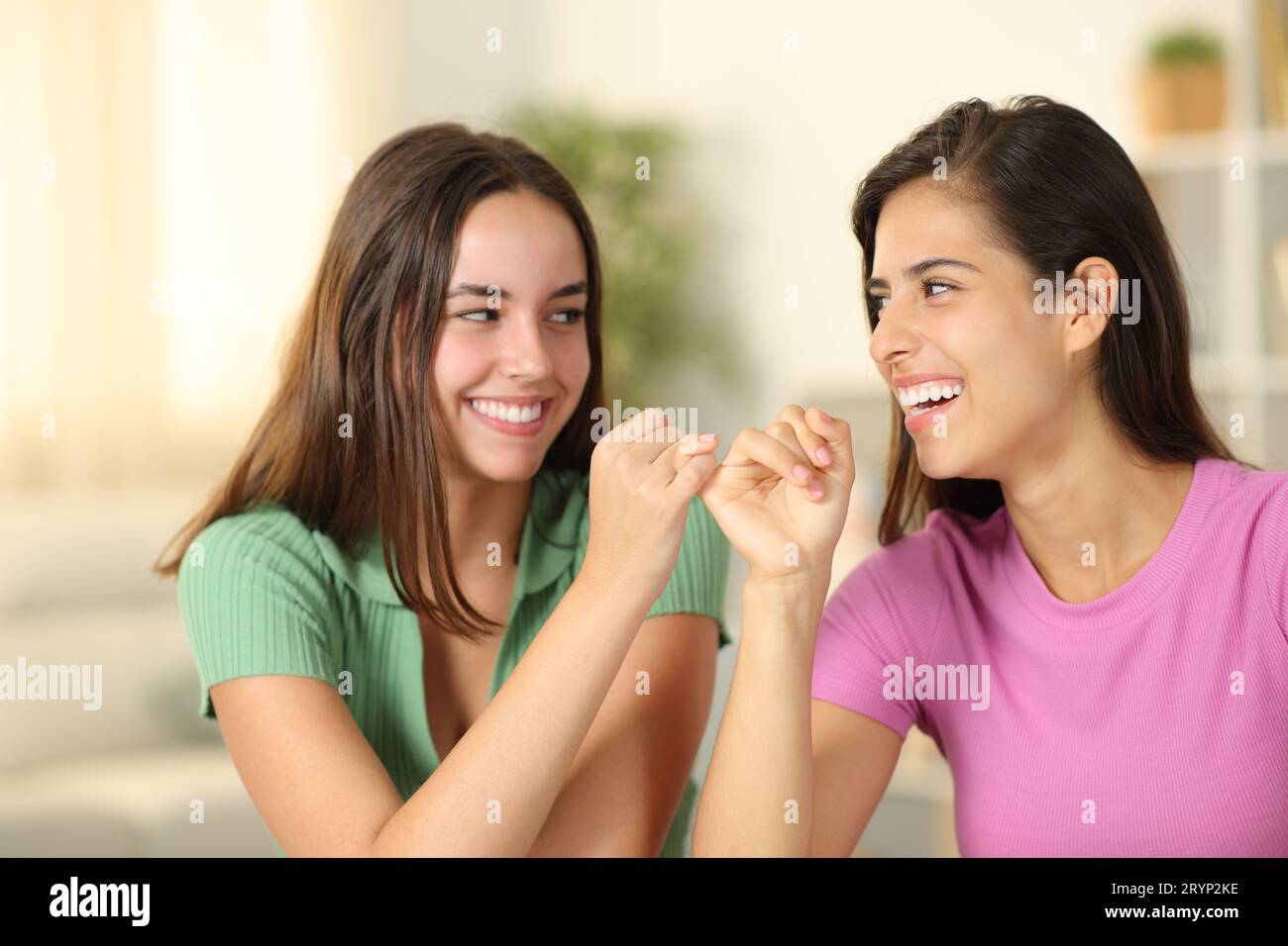 Two happy friends making pinky promise sitting at home Stock Photo - Alamy