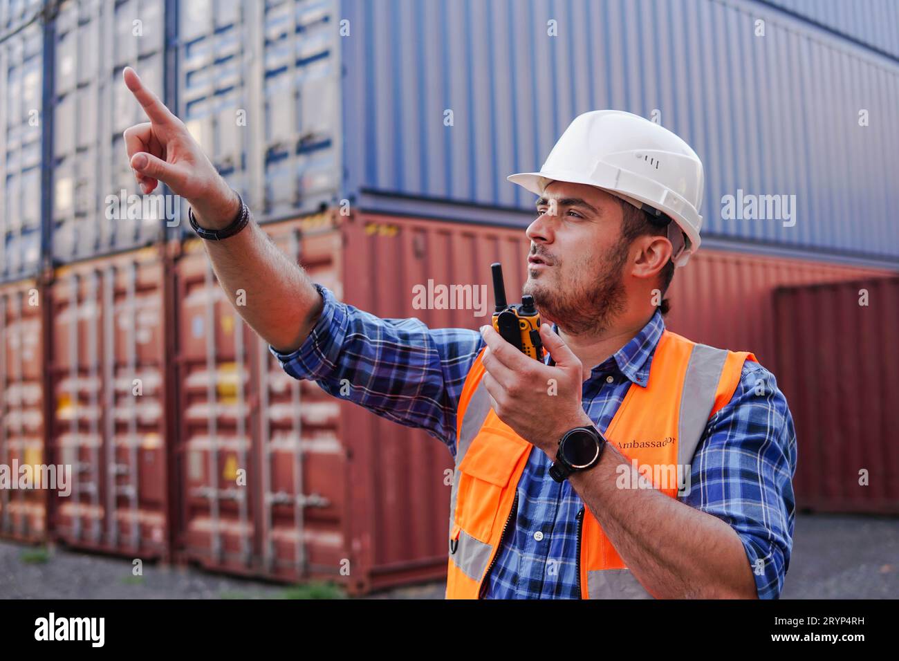Container man worker in white helmet talking radio phone or walkie ...
