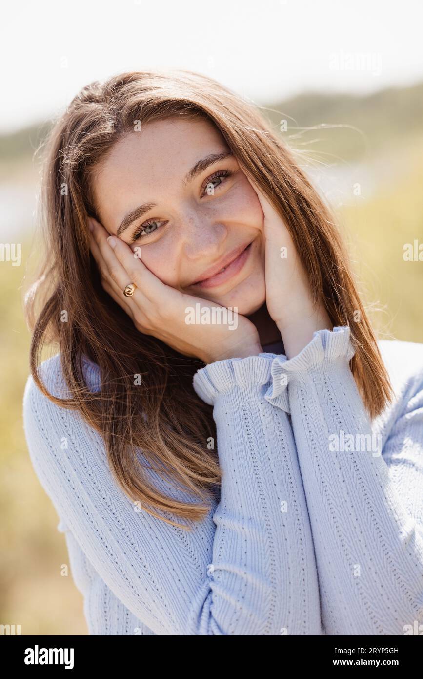 Happy beautiful girl holding her cheeks with a laugh, looking at the ...