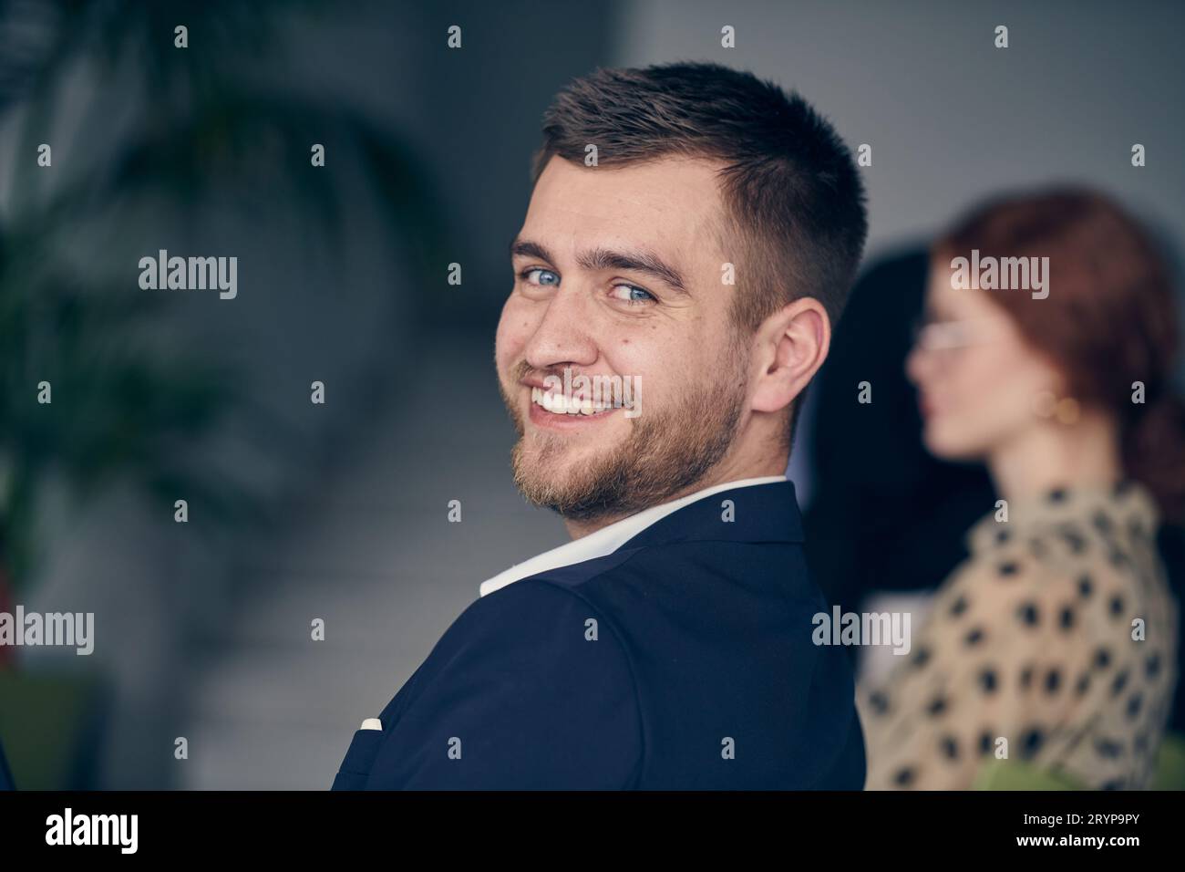 A smiling entrepreneur sits in a modern office, actively participating ...