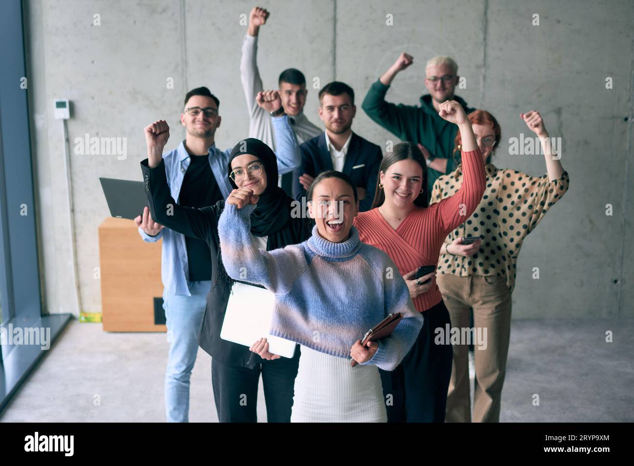 A diverse group of successful businessmen raises their hands in the air ...