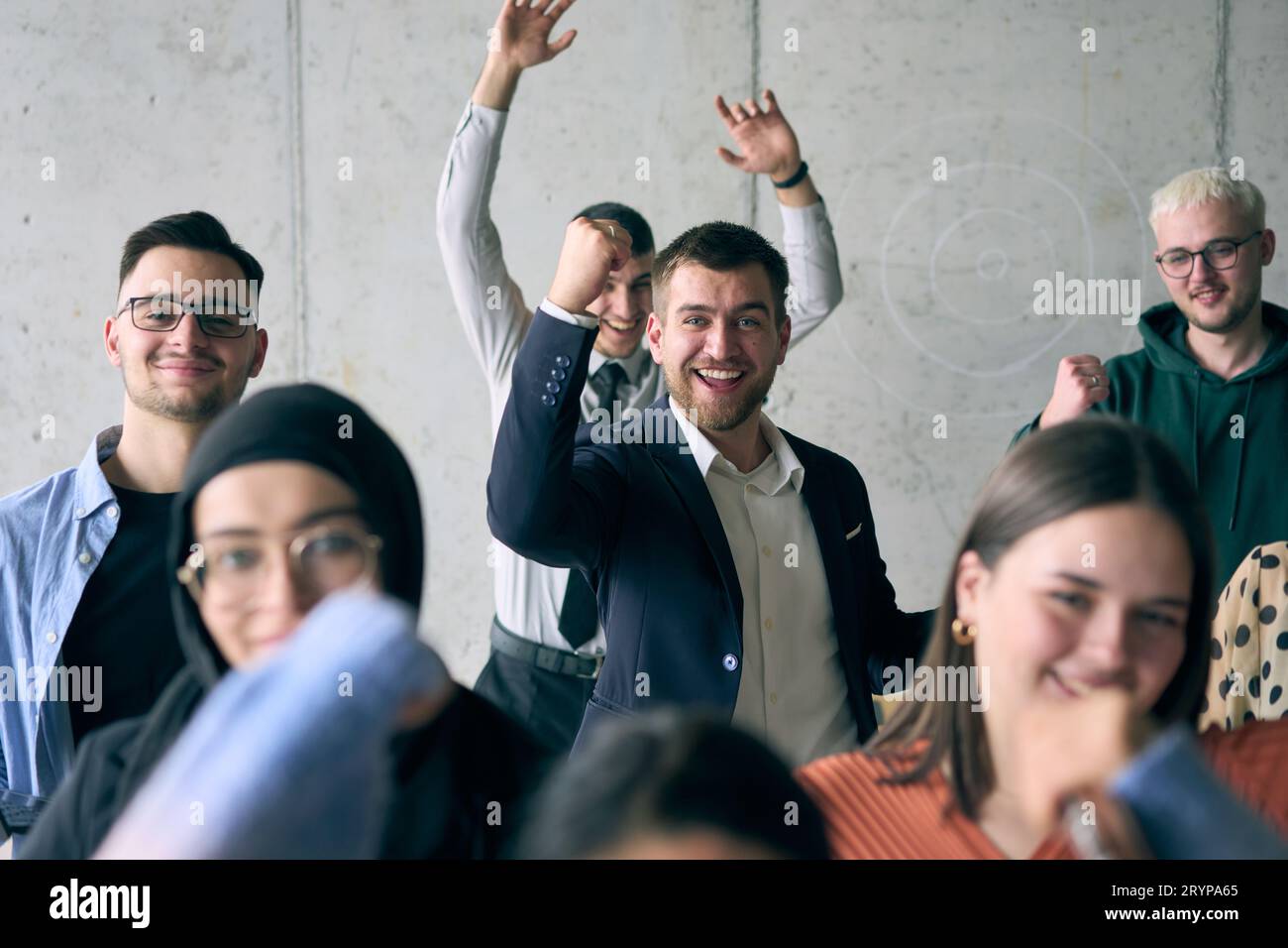 A diverse group of successful businessmen raises their hands in the air ...