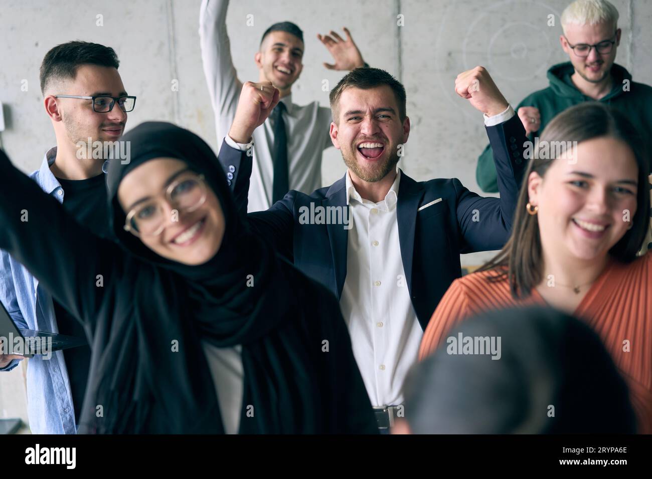 A diverse group of successful businessmen raises their hands in the air ...
