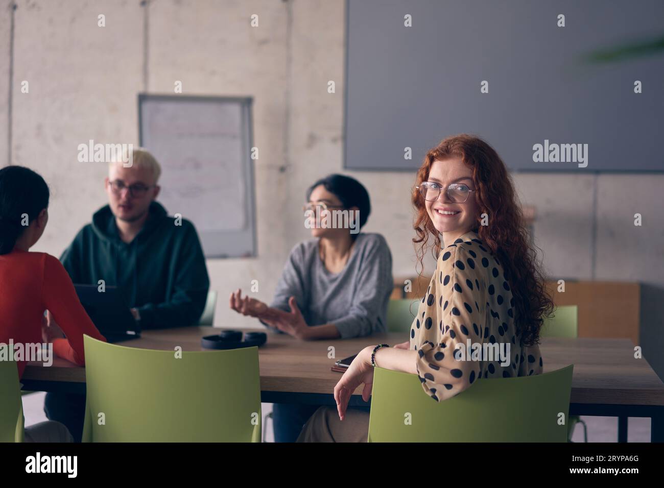 A diverse group of business professionals gathered at a modern office ...