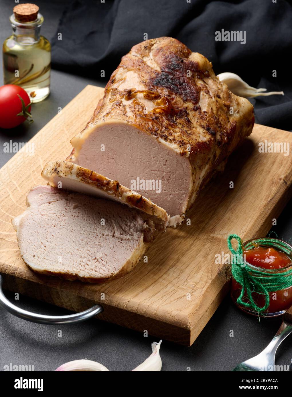 Baked piece of pork balyk on the table with spices. Tenderloin cut into ...