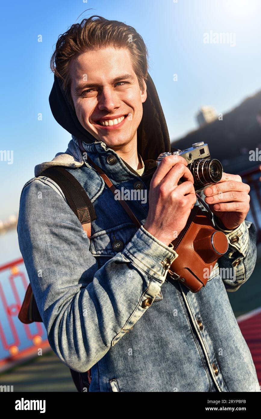 Young cheerful man photographer taking pictures with camera Stock Photo ...