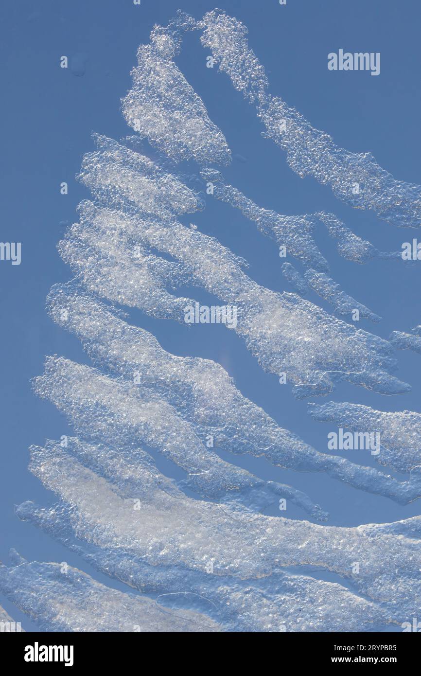 Melting snow and ice forms cloud-like patterns on a skylight window ...